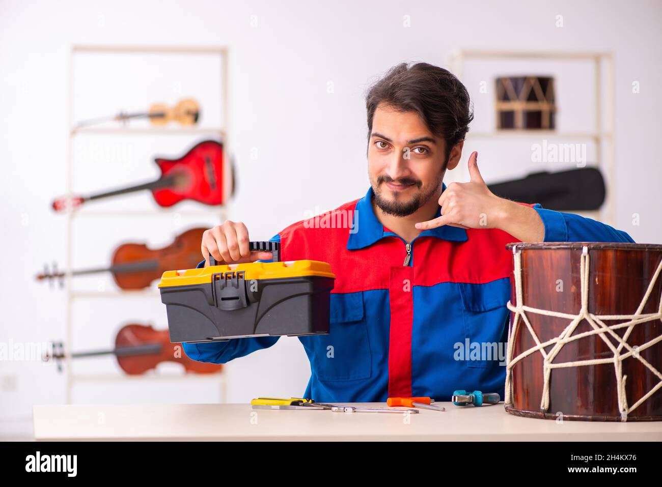 Young repairman repairing musical instruments at workplace Stock Photo ...