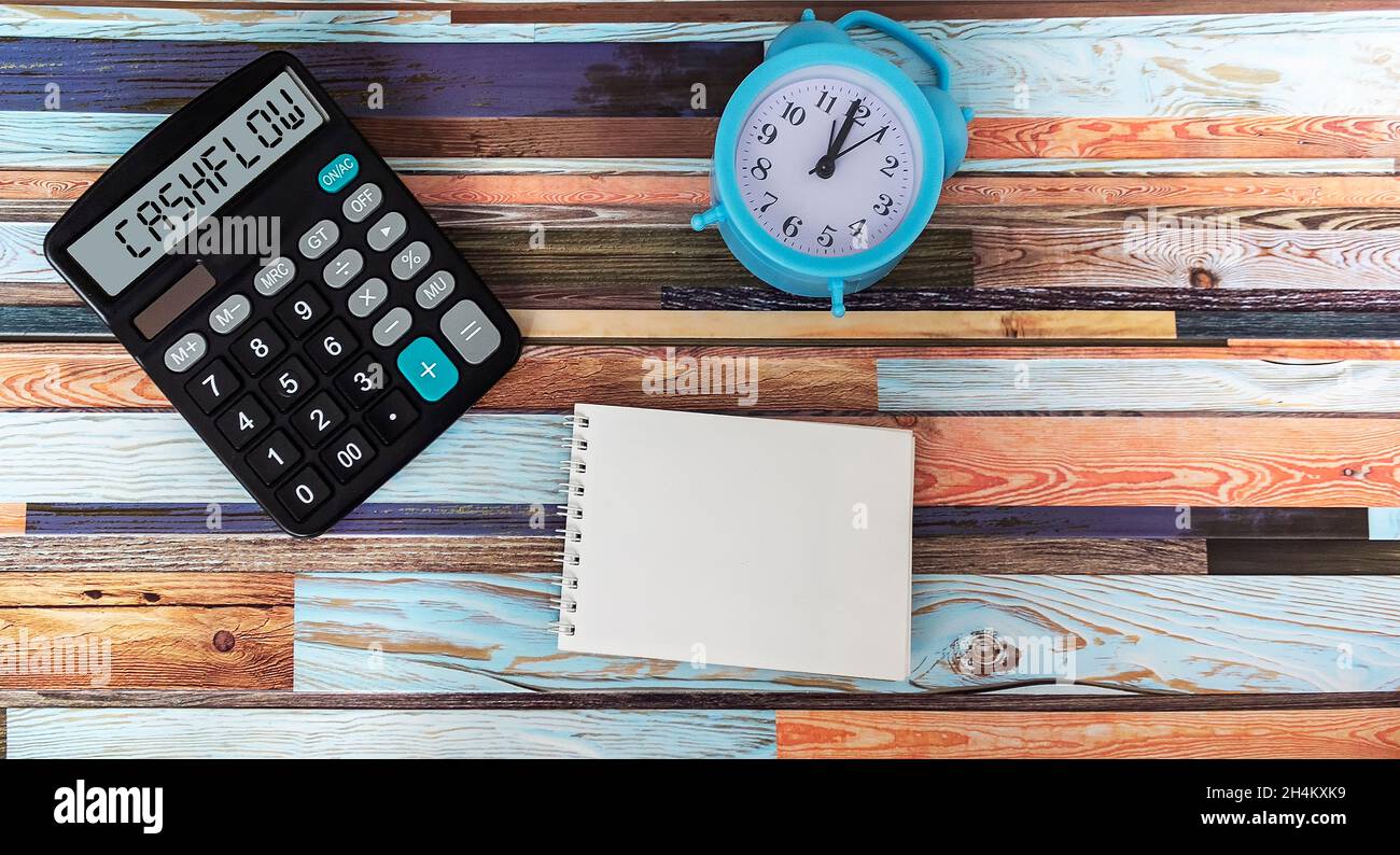 Calculator with the words Cash Flow, an alarm clock stands next to them ...