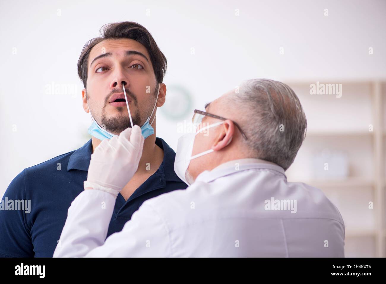 Young patient visiting old male doctor during pandemic Stock Photo - Alamy