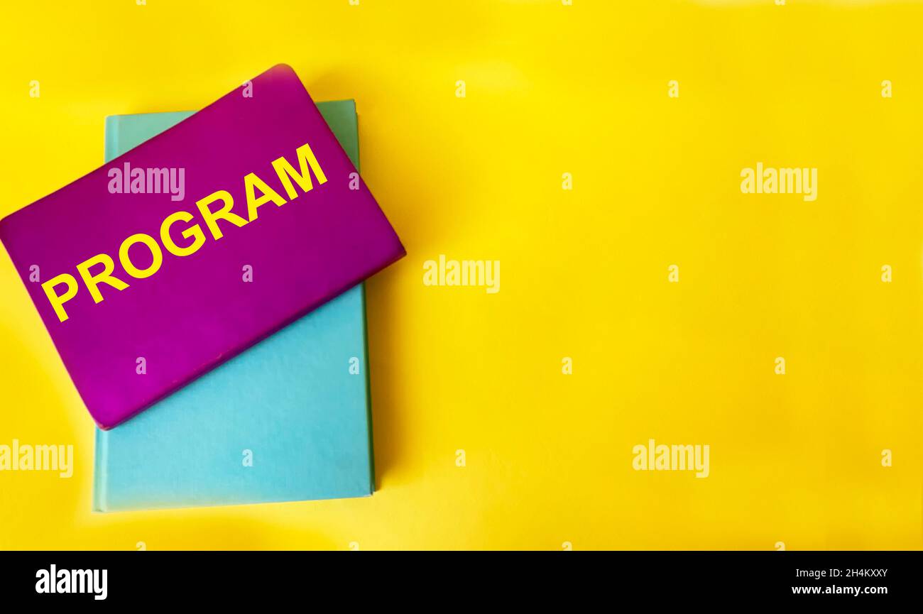 concept of the word PROGRAM on a crimson notebook and on a yellow ...