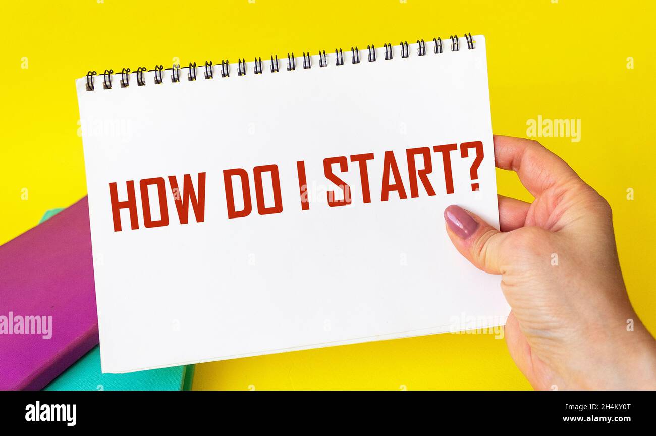 How do i start , text is written on paper held by female hand on yellow ...