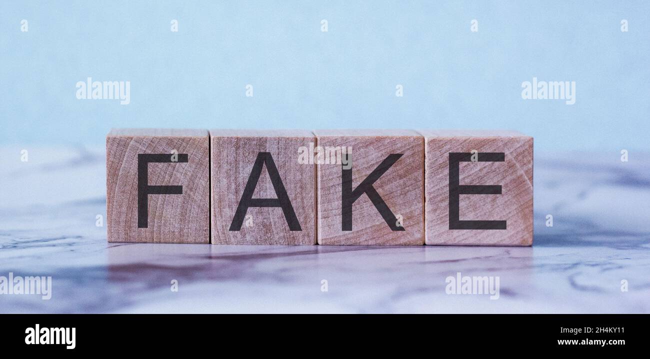 FAKE word made with building blocks isolated on blue Stock Photo - Alamy