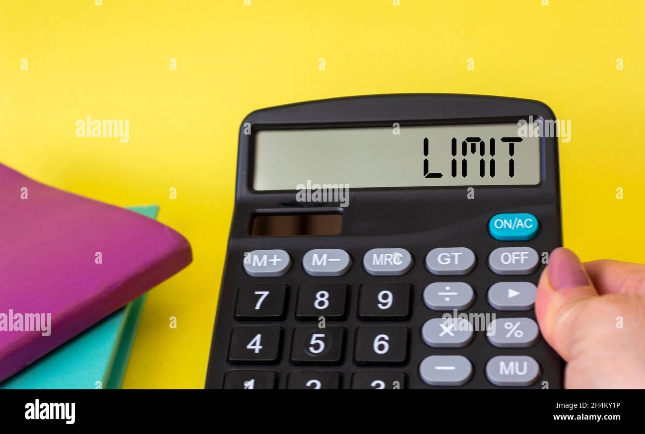Female hand on a calculator with the text LIMIT on the display. Multi ...