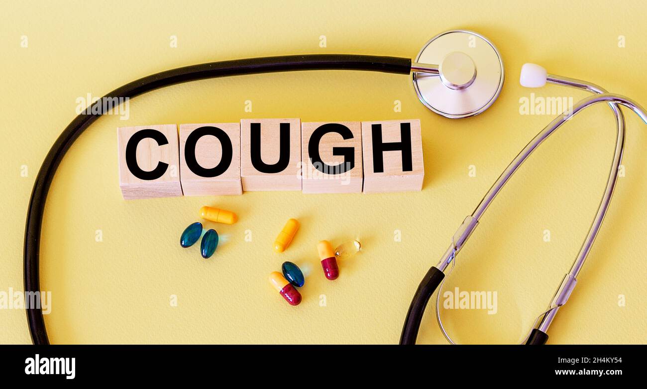 the word Cough written on a wooden block. cough text on a yellow ...
