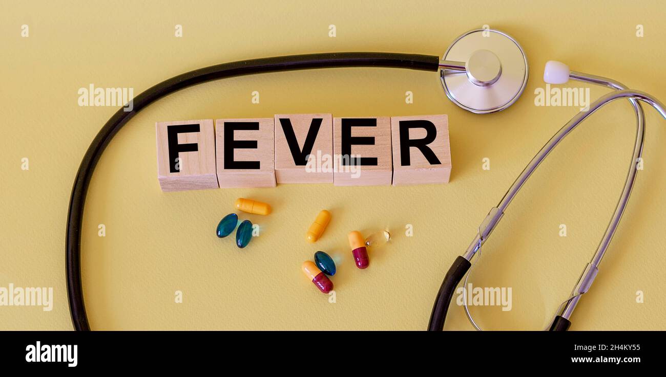 The word Fever written on a wooden block. There is a stethoscope and ...