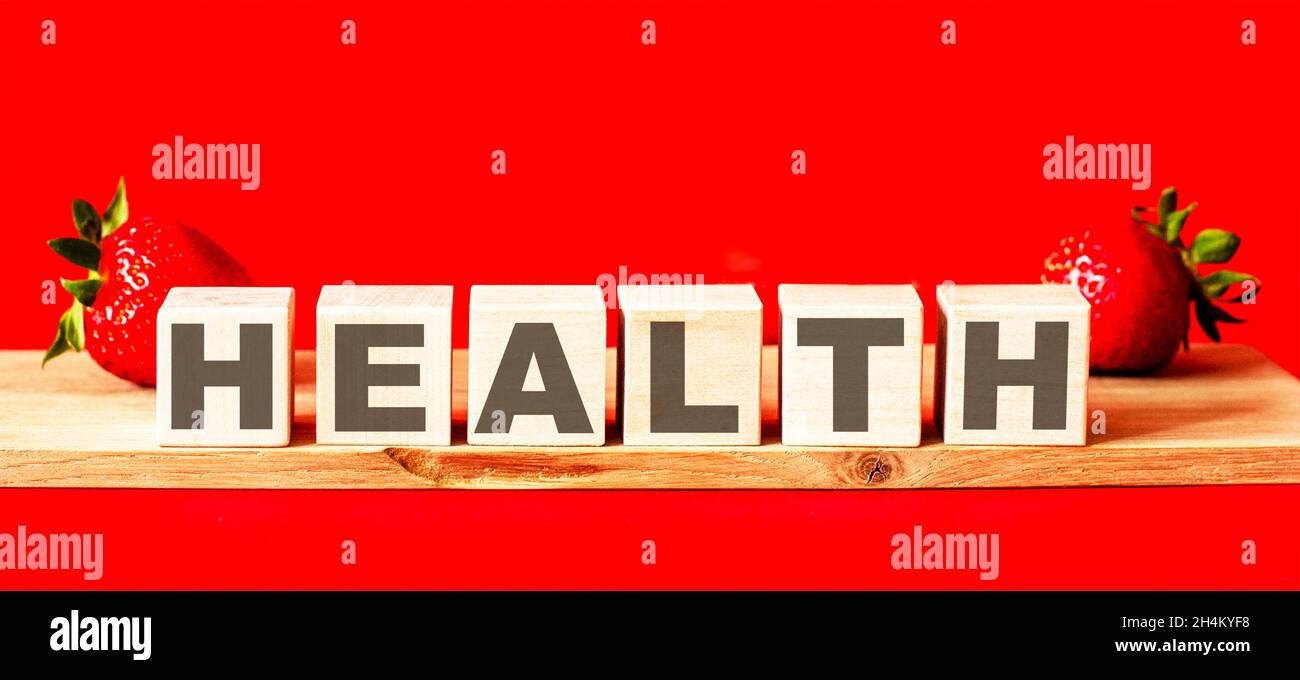 HEALTH text from wooden cubes on a wooden background with strawberries ...