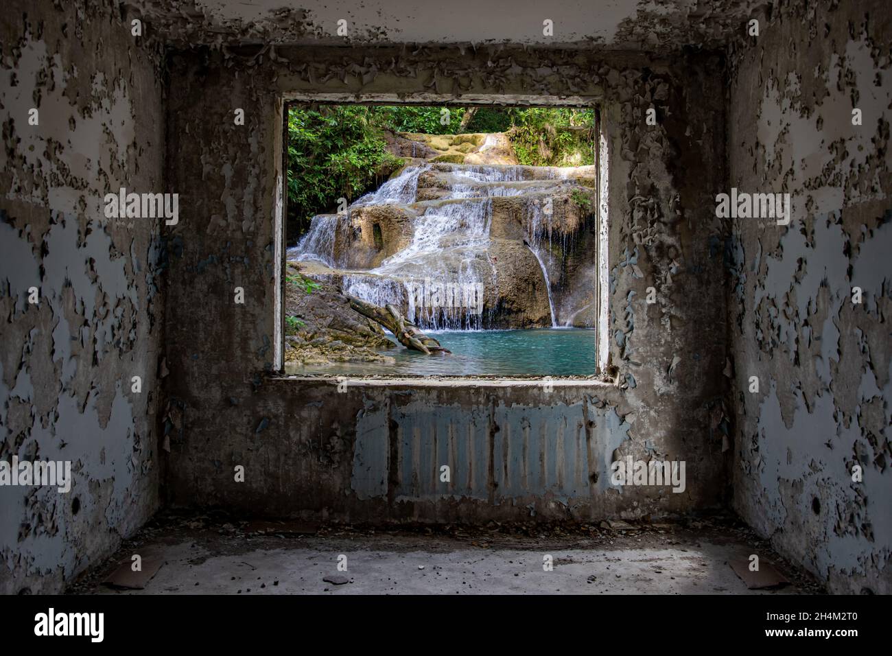 View of a tropical waterfall through a window hole in a damaged ...