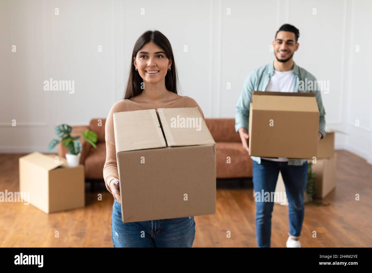 Relocation Concept. Happy millennial lady holding cardboard box walking ...