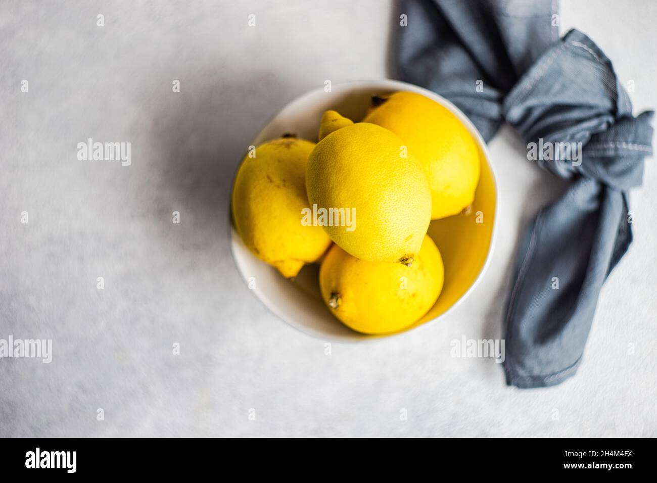 Organic raw and ripe lemon fruits in a bowl on white concrete ...