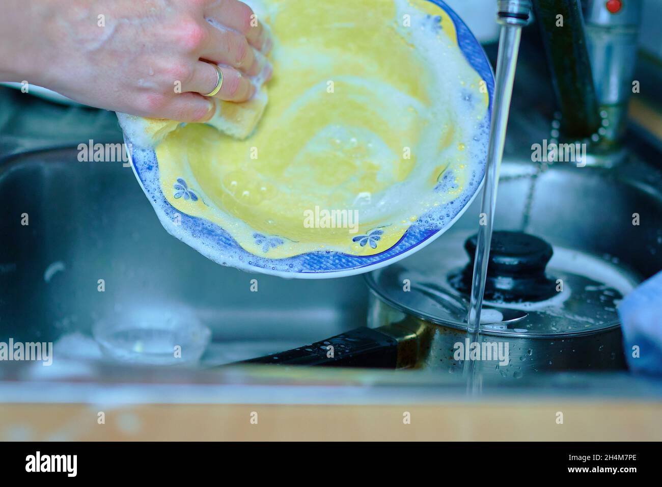 housewife washing dishes in the kitchen sink after the meal. cleaning ...