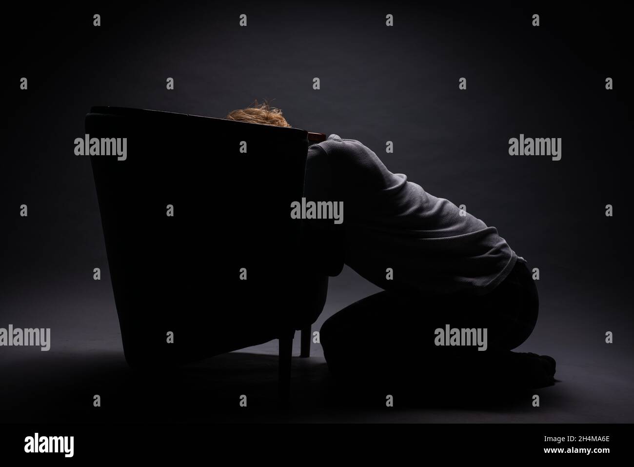 Depressed and sad boy is crying on the chair while suffering from the ...