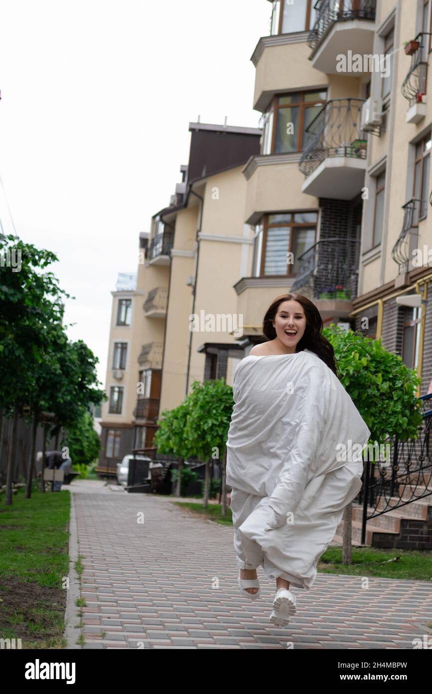 pretty brunette woman in white blanket outdoors. crazy rebel millennial girl Stock Photo - Alamy