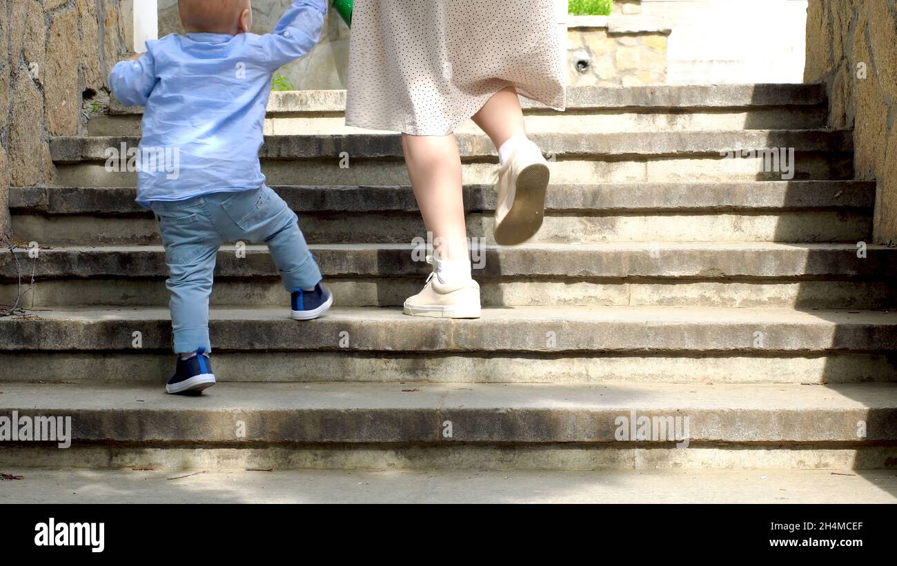 Close-up of mother and child climb steps. Stock footage. Back view of ...