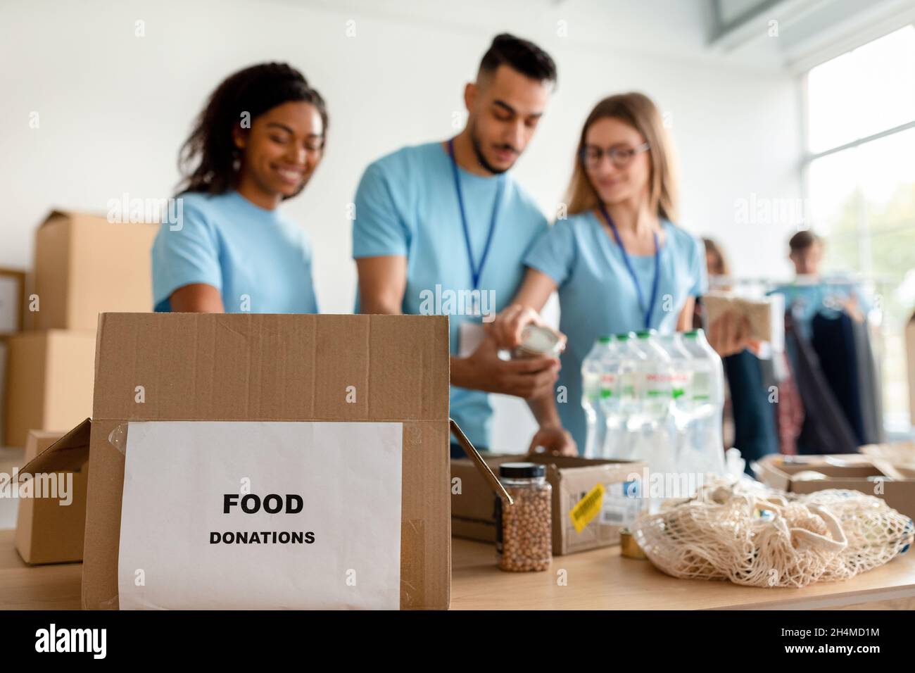 Focus on food donation box. Diverse volunteers sorting and packing ...