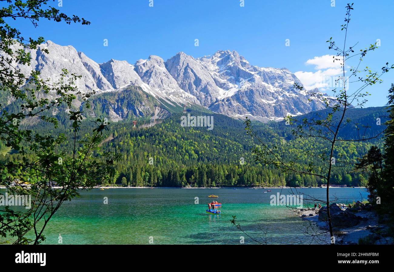 a red pedal boat on turquoise lake Eibsee by the foot of mountain ...