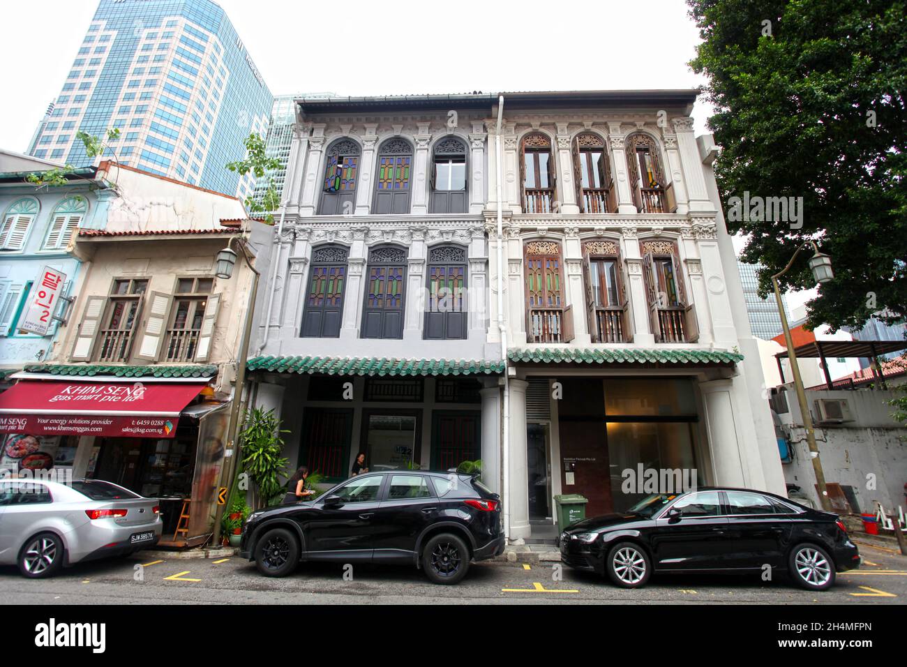 Old shop house buildings with parked cars and commercial businesses in ...