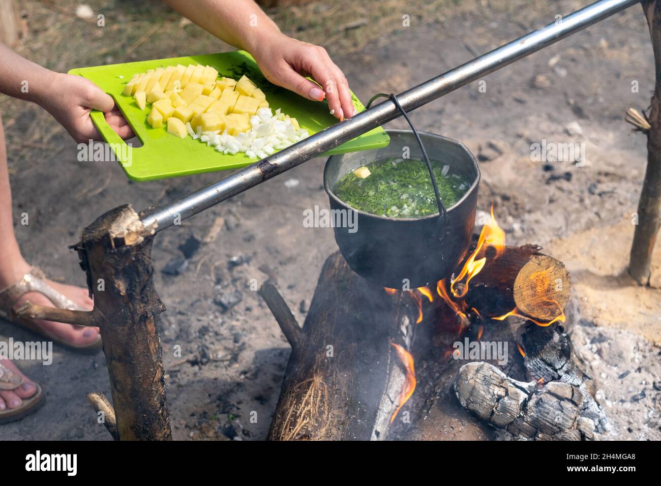 throw the ingredients into the soup which is cooked over a fire in a ...