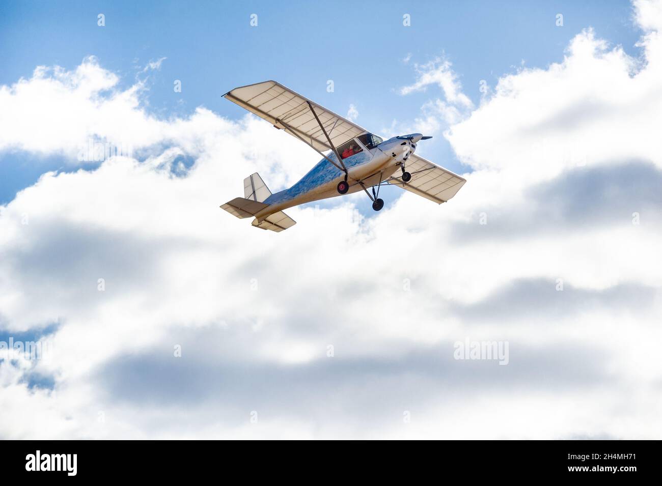 A small single-engine plane flying overhead against the blue sky Stock ...