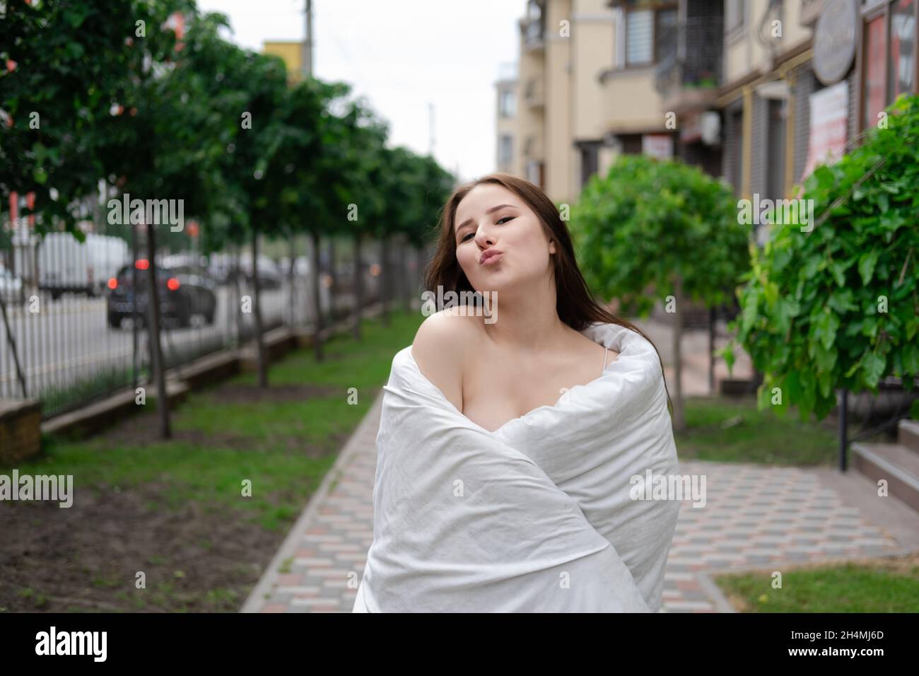 pretty brunette woman in white blanket outdoors. crazy rebel millennial girl Stock Photo - Alamy