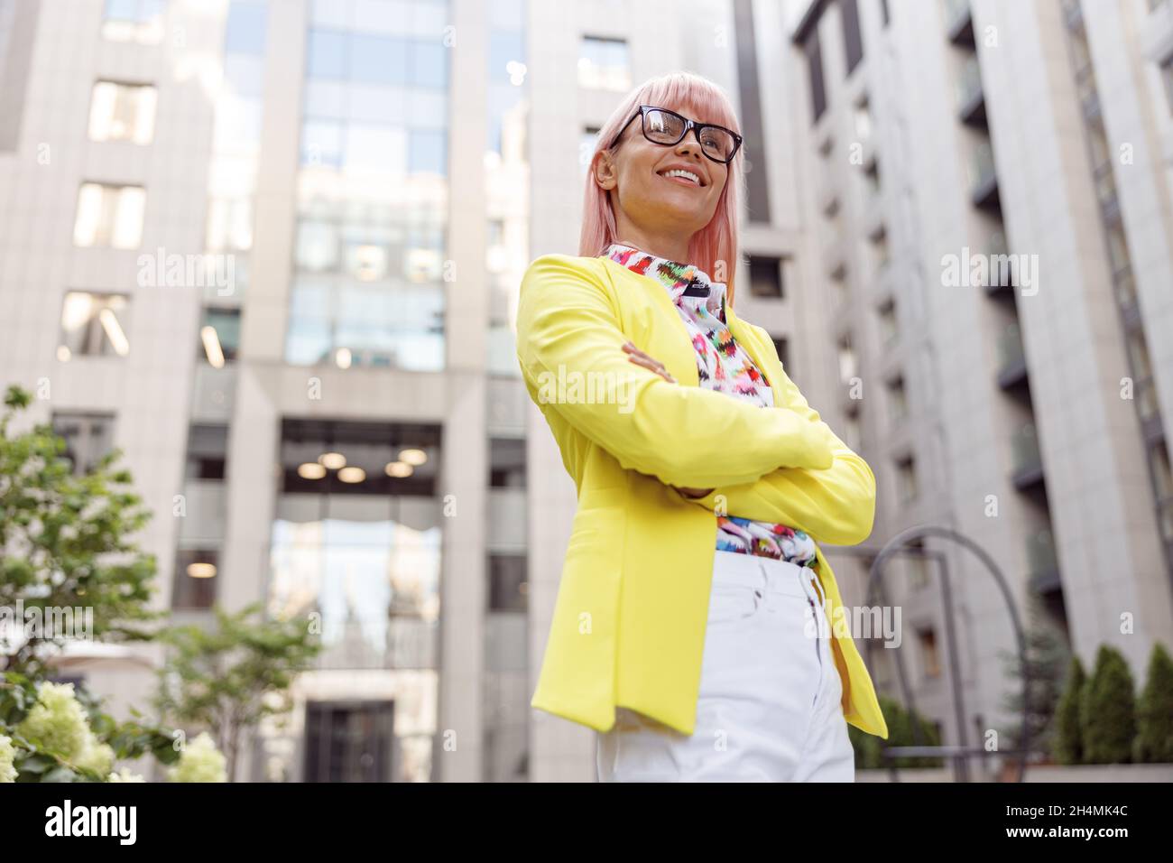 Proud lady with folded arms watching something before her outdoors ...