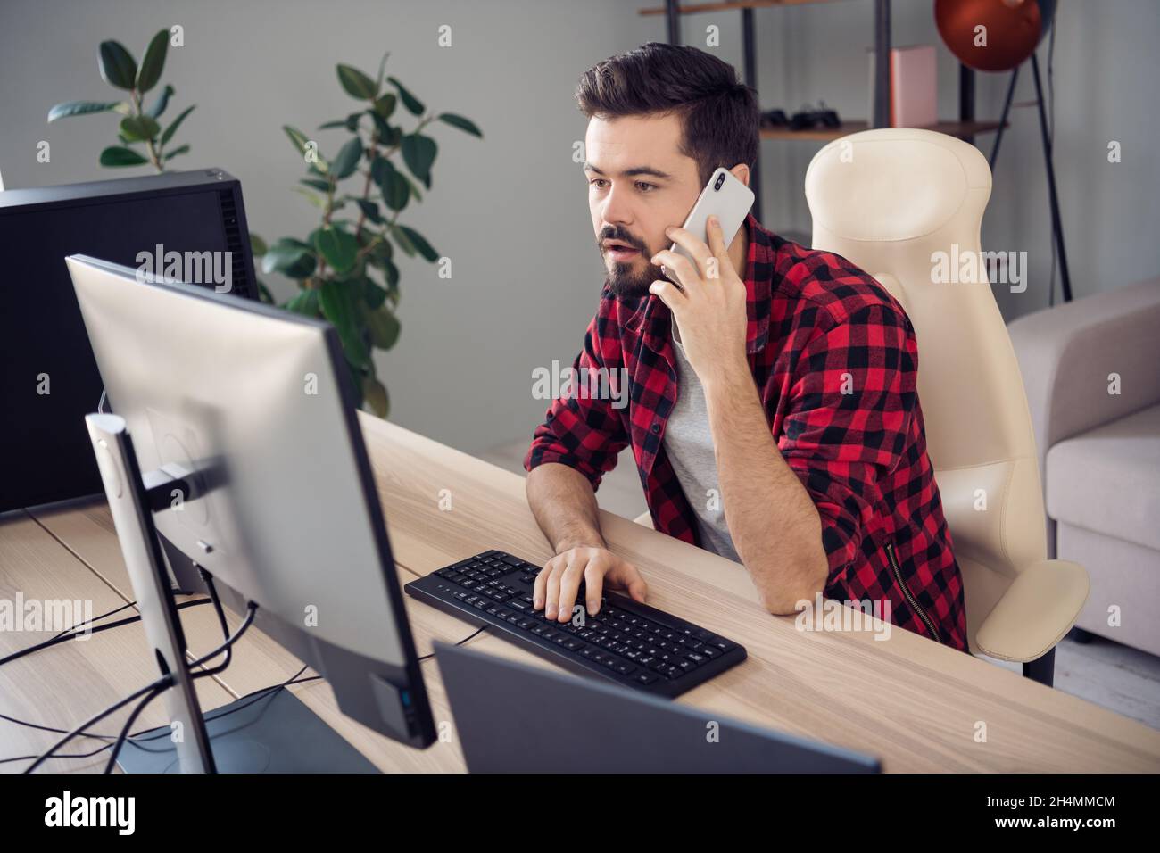 Photo of serious focused young man write computer programmer hold phone ...