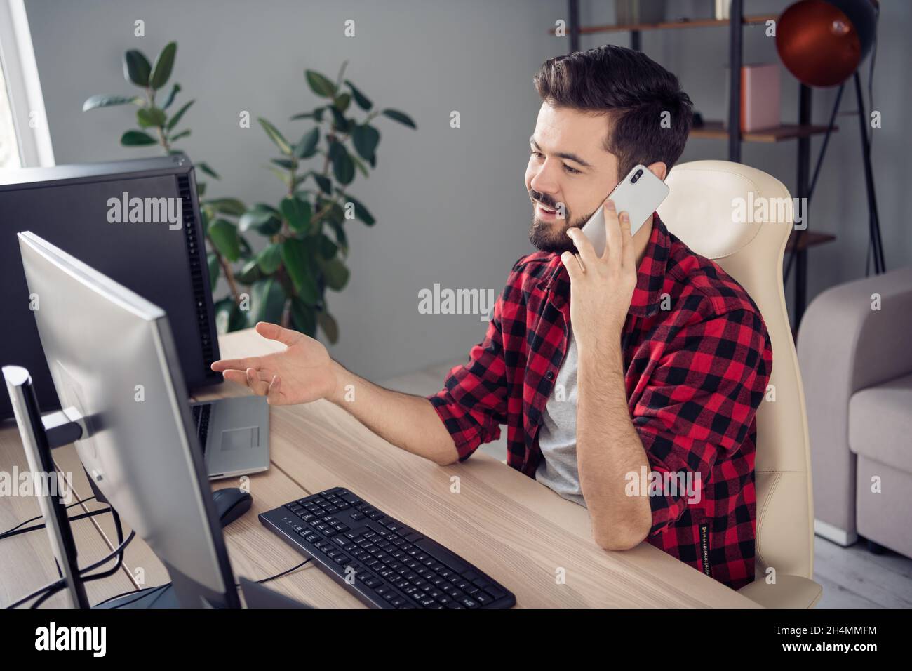Photo of charming happy young man talk phone sit desk good mood job ...