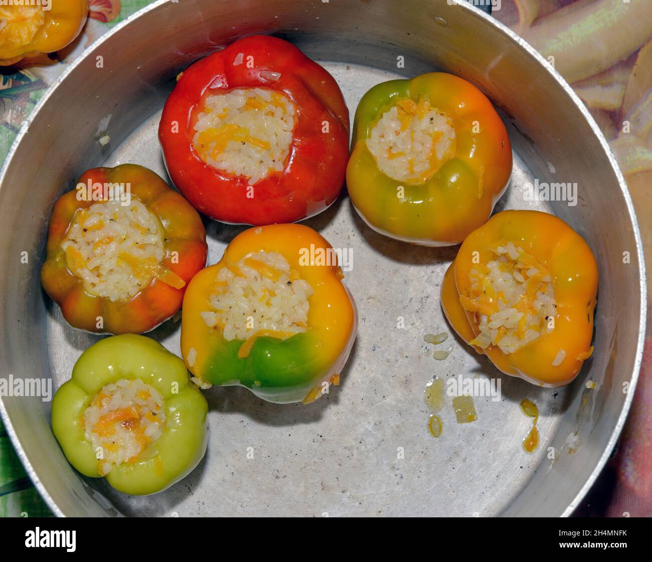 Close-up of steps of putting stuffed with rice and carrots bell peppers into aluminum saucepan ...