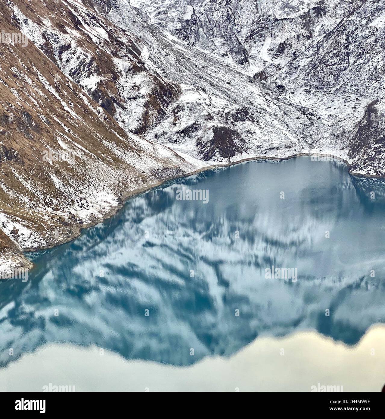 Small clear lake in between the snowy mountain chain in cold winter, in ...
