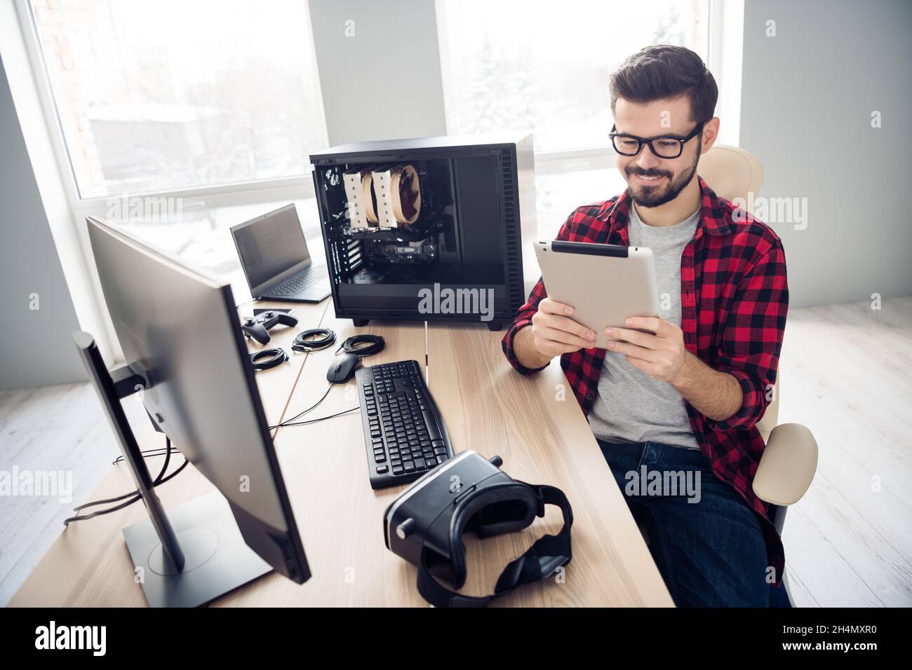 Portrait of attractive trendy focused cheerful smart guy reading tech ...