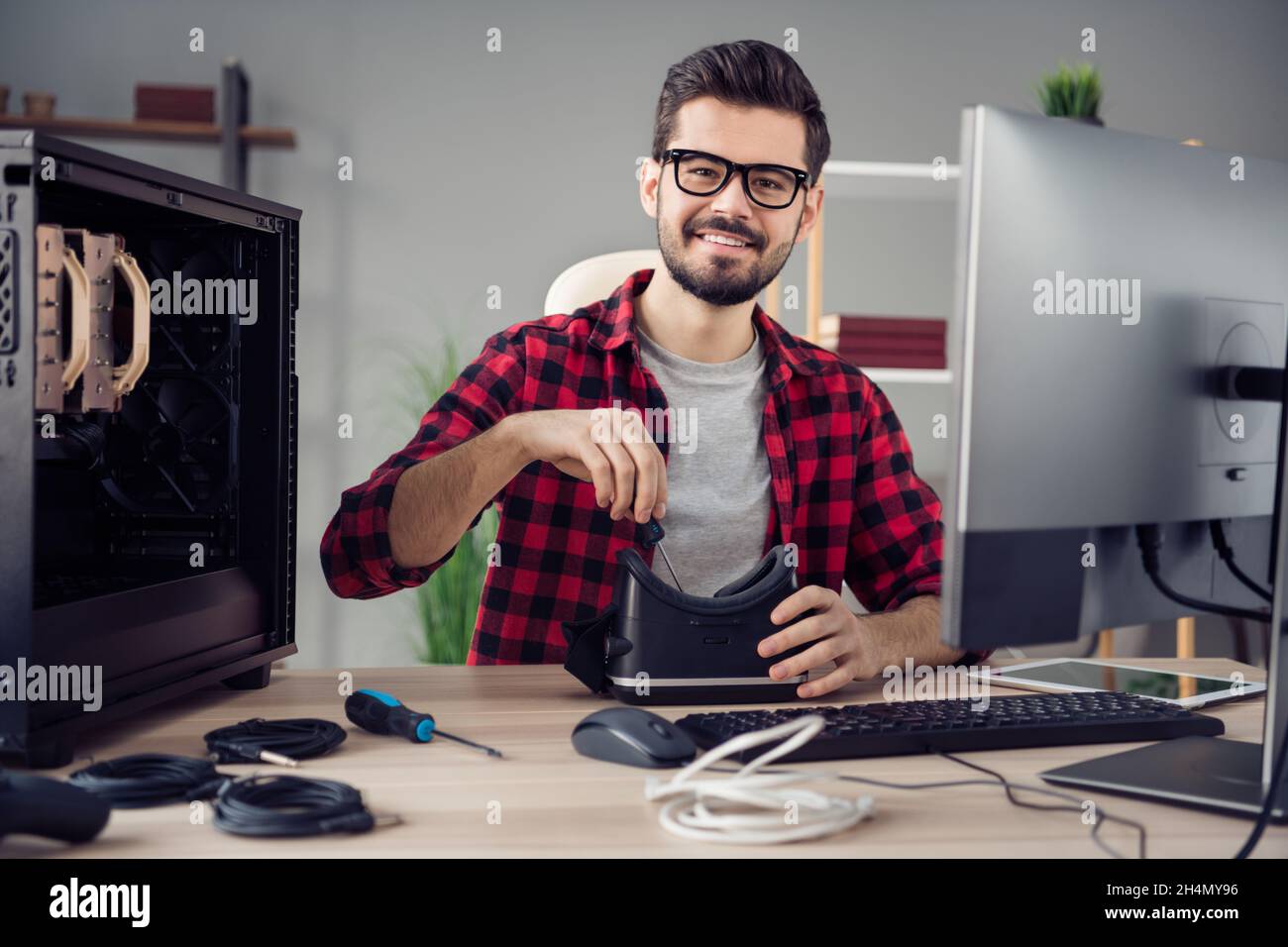 Portrait of attractive cheerful experienced guy fixing improving vr ...