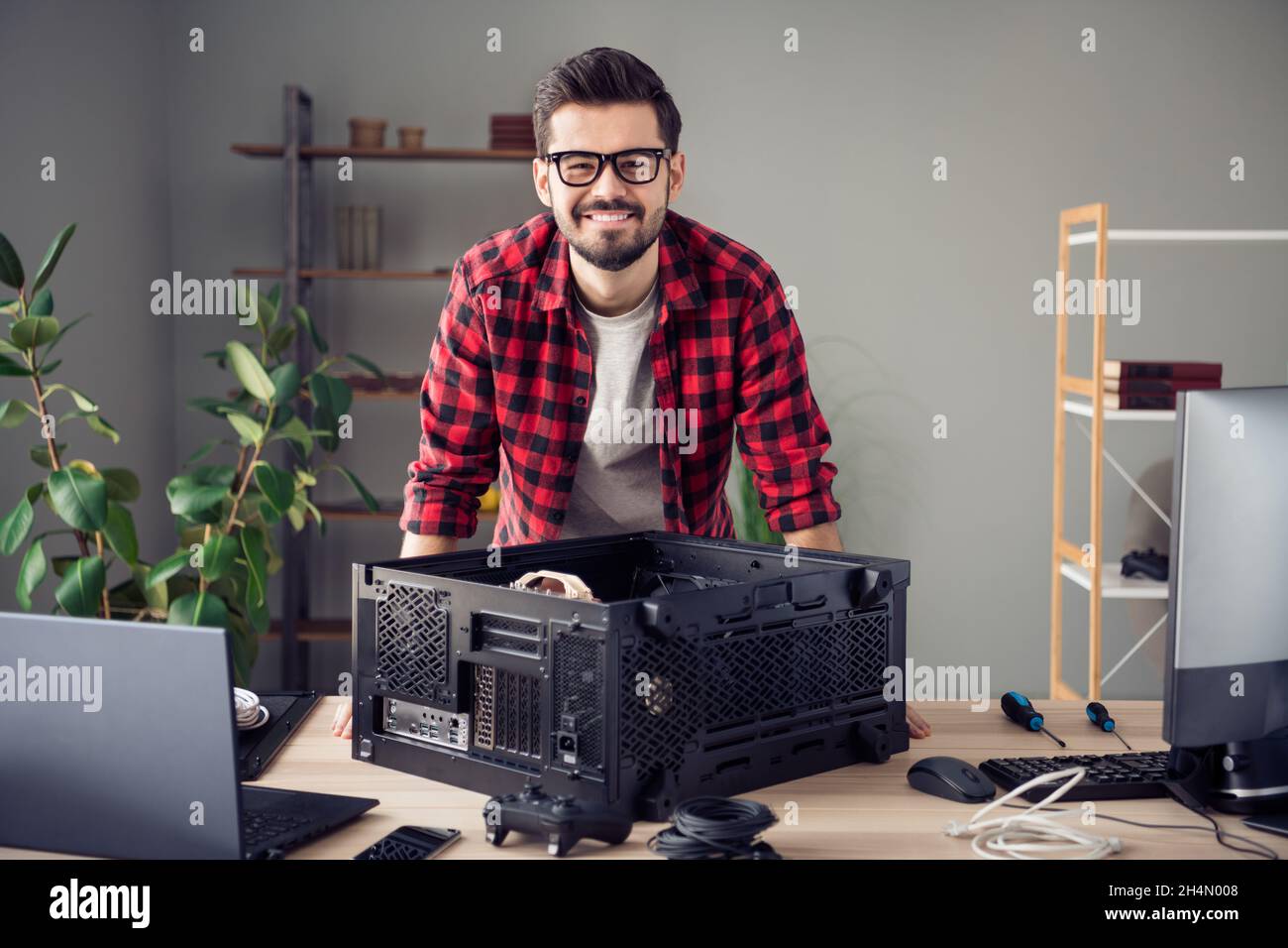 Portrait of attractive smart bearded cheerful trendy guy upgrading processor data tech issue at ...