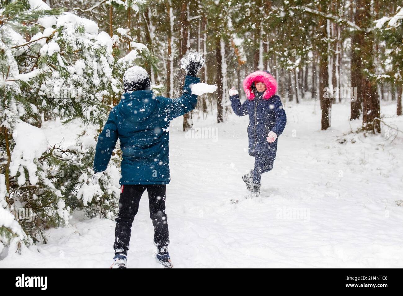 The boy swinging a snowball with a girl. Funny children in Winter Park ...