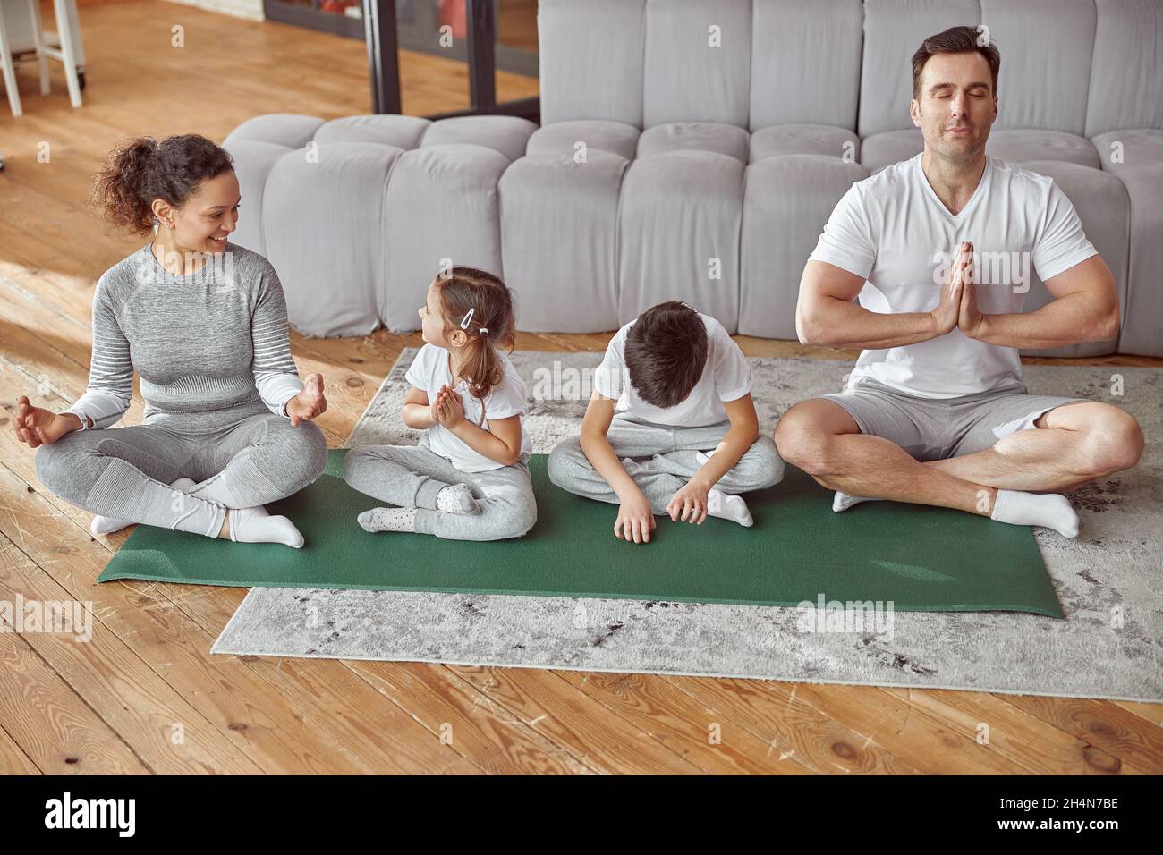 Cheerful parents teaching kids doing meditation at home Stock Photo - Alamy