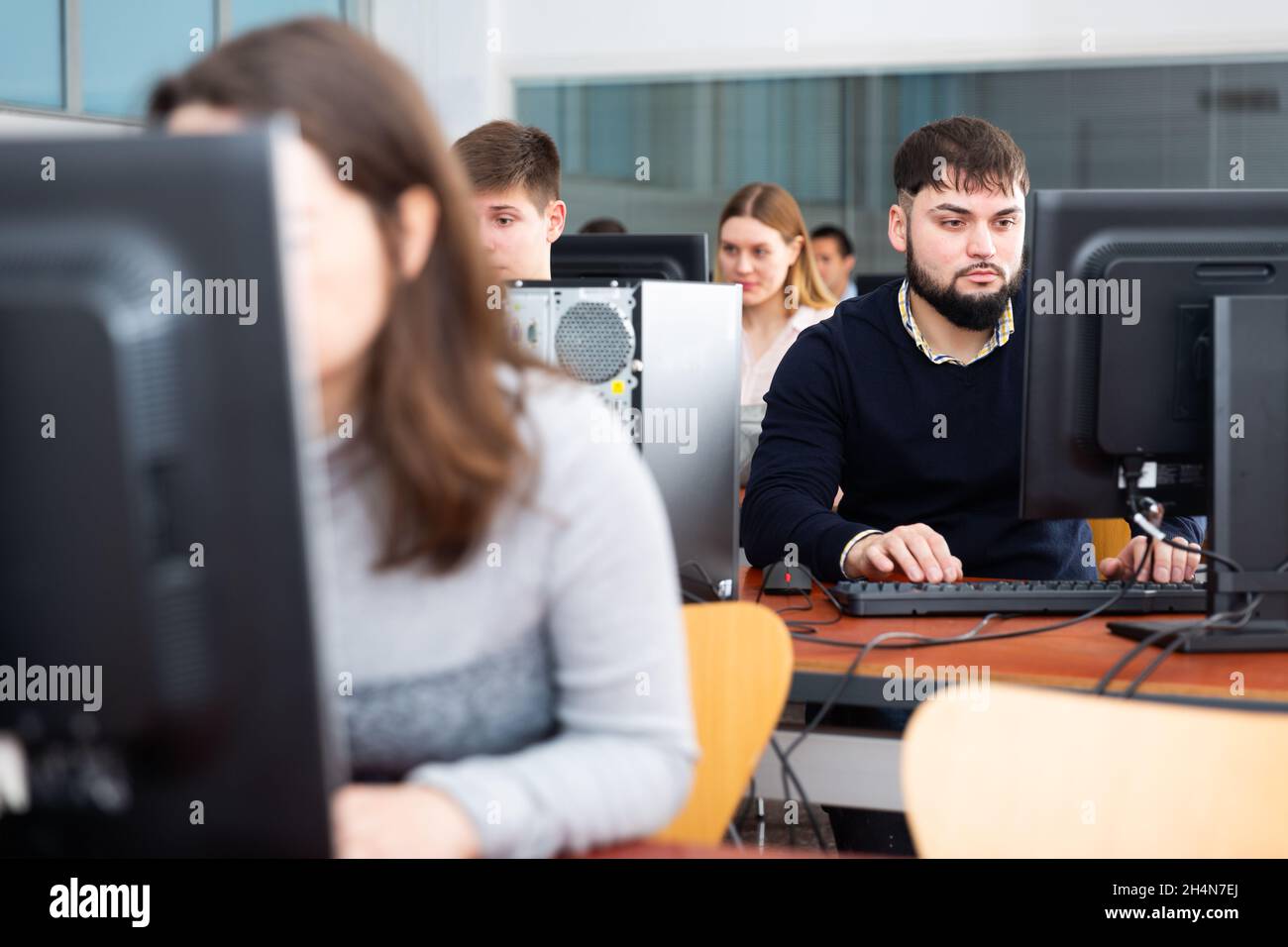 Portrait of female and male students working on computers in classroom ...