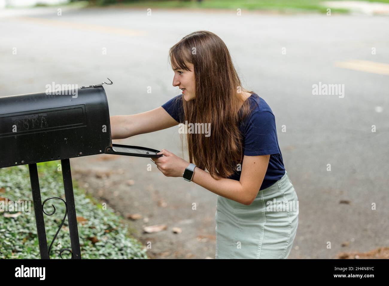 A teen brunette girl with long hair checking the mailbox for letters ...