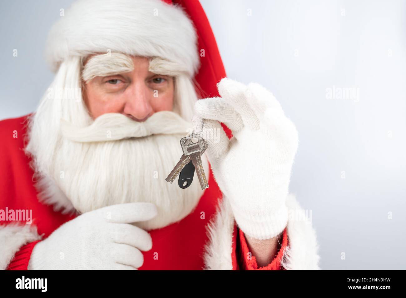 Santa Claus holds keys on a white background. New home gift for ...