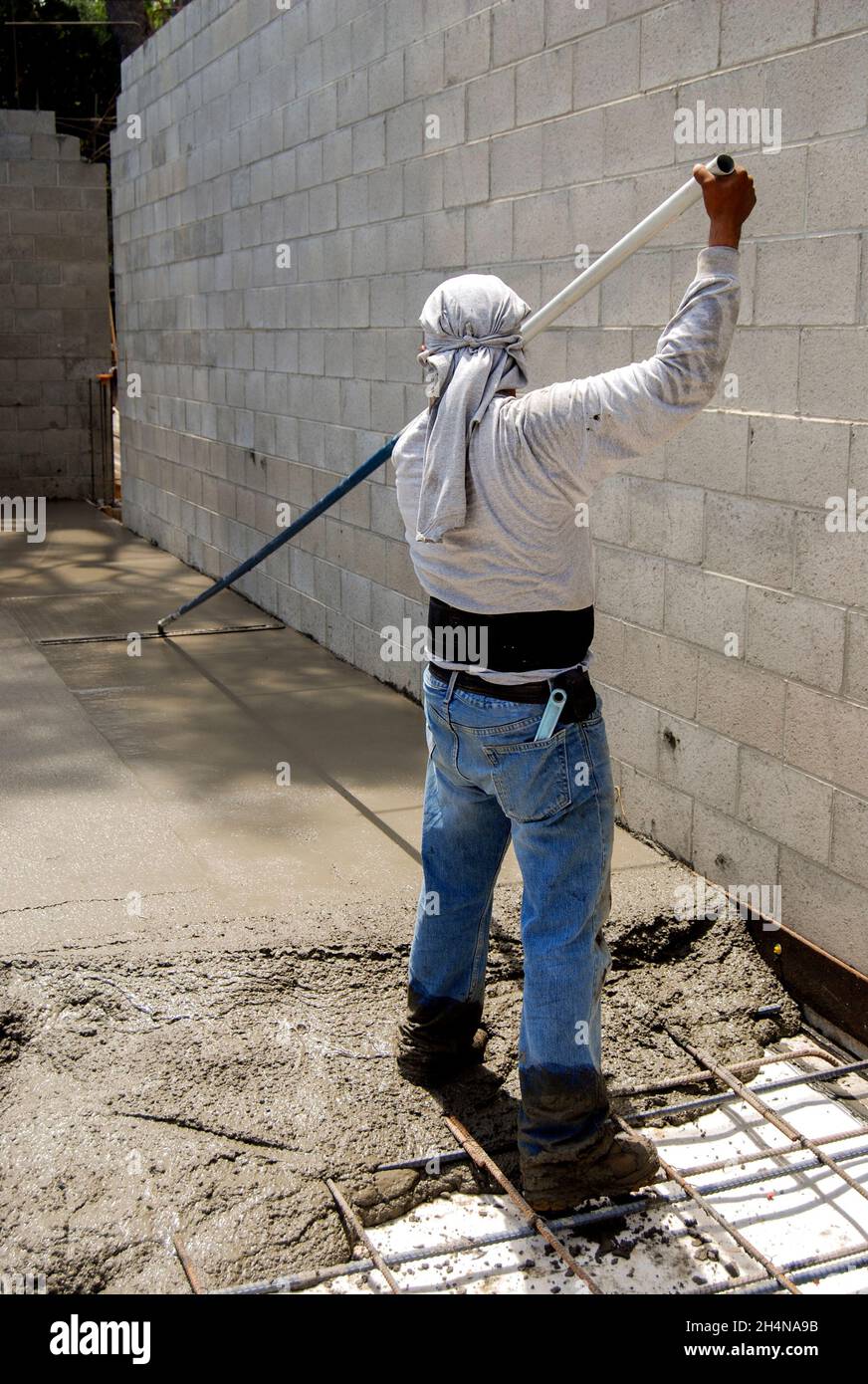 Mason using a bull float to level and smooth a new slab on grade Stock ...