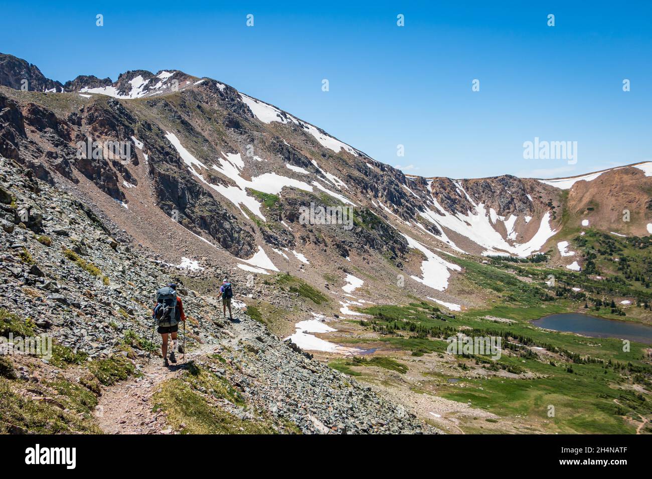 Hikers backpacking with heavy packs and hiking poles in rugged mountain ...