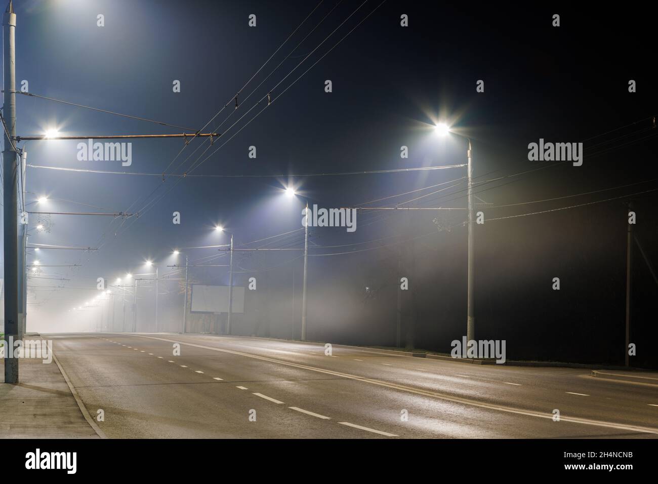 empty foggy night road with rows of lamp posts Stock Photo - Alamy