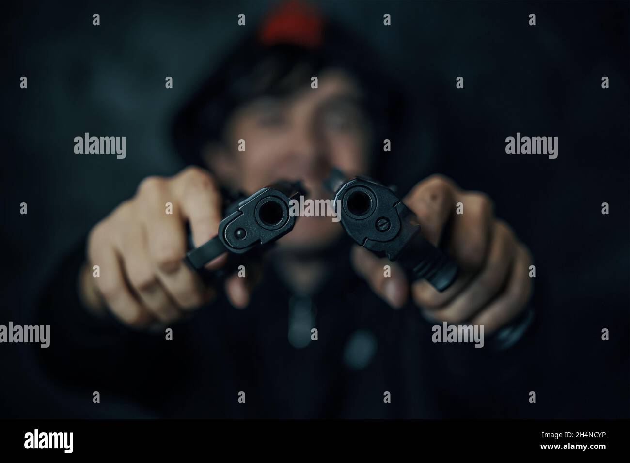 Two pistols in man's hands are pointed at camera. Guy threatens with ...