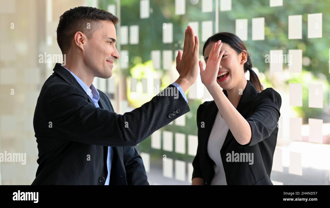 Cheerful businessman and businesswoman giving high five, excited happy ...