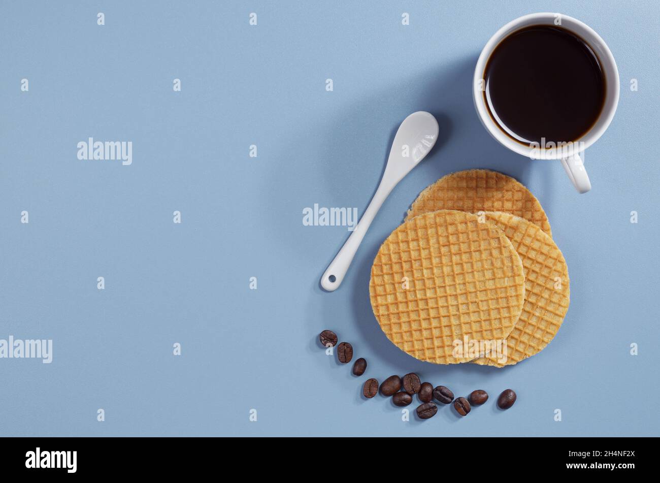 Cup of coffee and round wafers on blue table, top view with space for ...