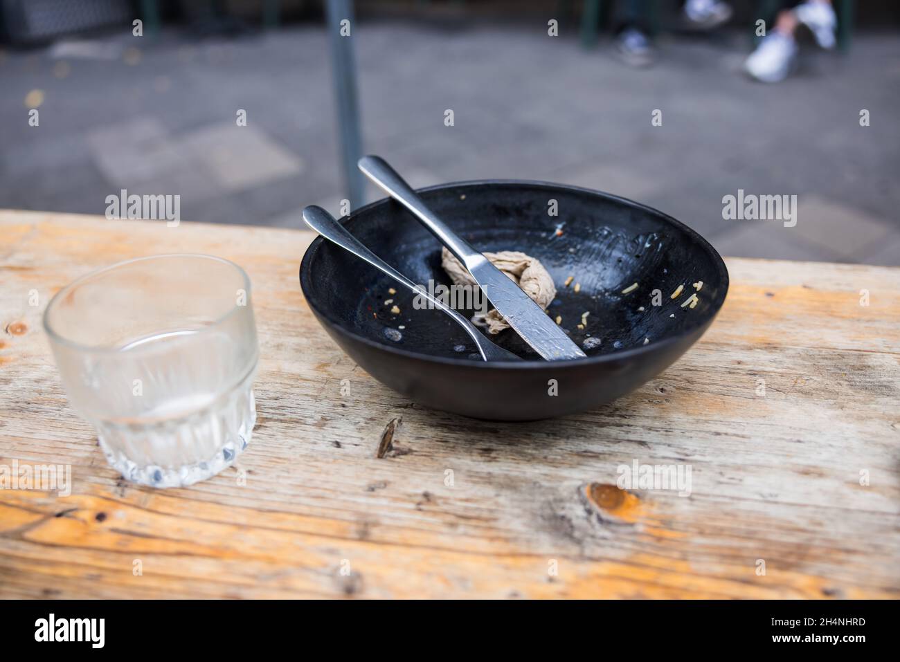 Almost empty bowl and empty water glass left by a customer after eating ...