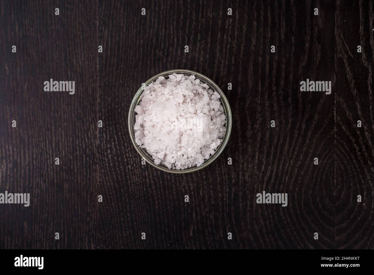 Salt in a glass bowl - top view. On black background Stock Photo - Alamy