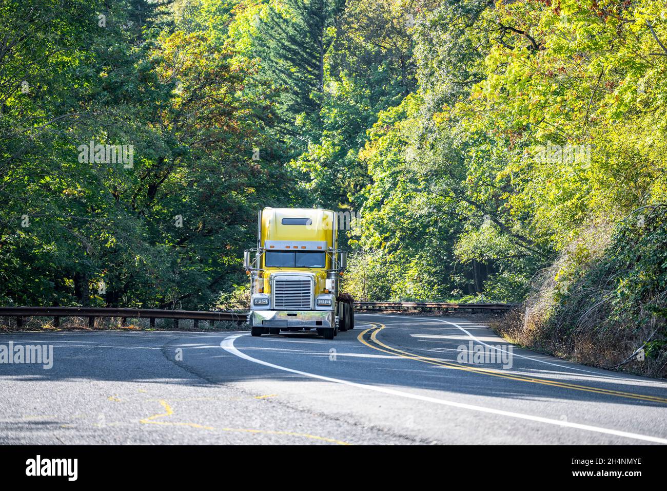 Powerful yellow big rig classic semi truck transporting fixed by slings ...