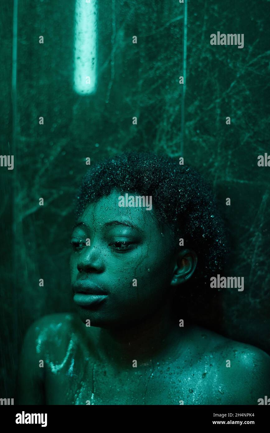 African young woman in depression leaning on the wall while washing in ...