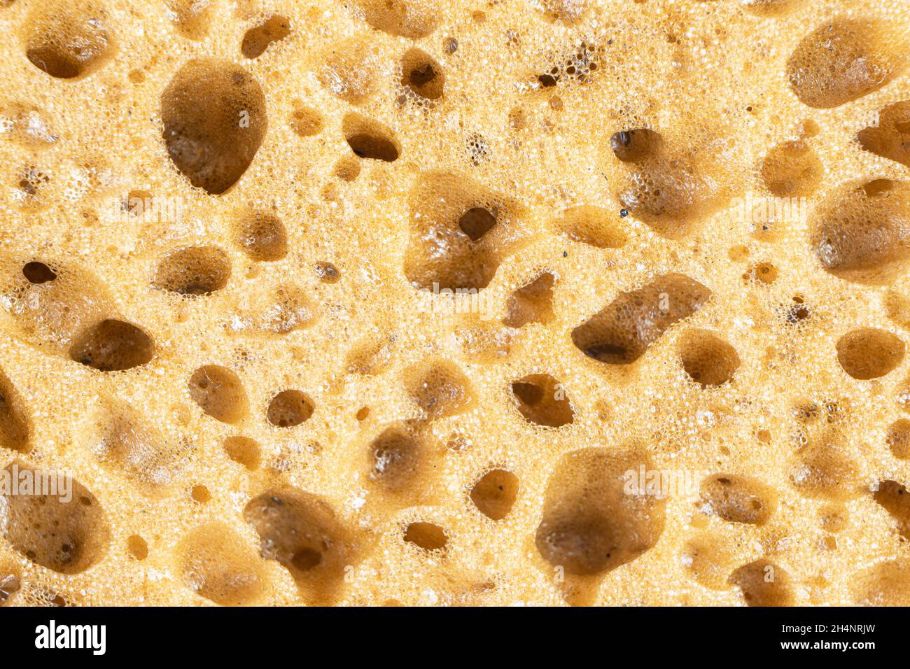 Macro shot of a surface of plastic yellow sponge background. Close-up ...