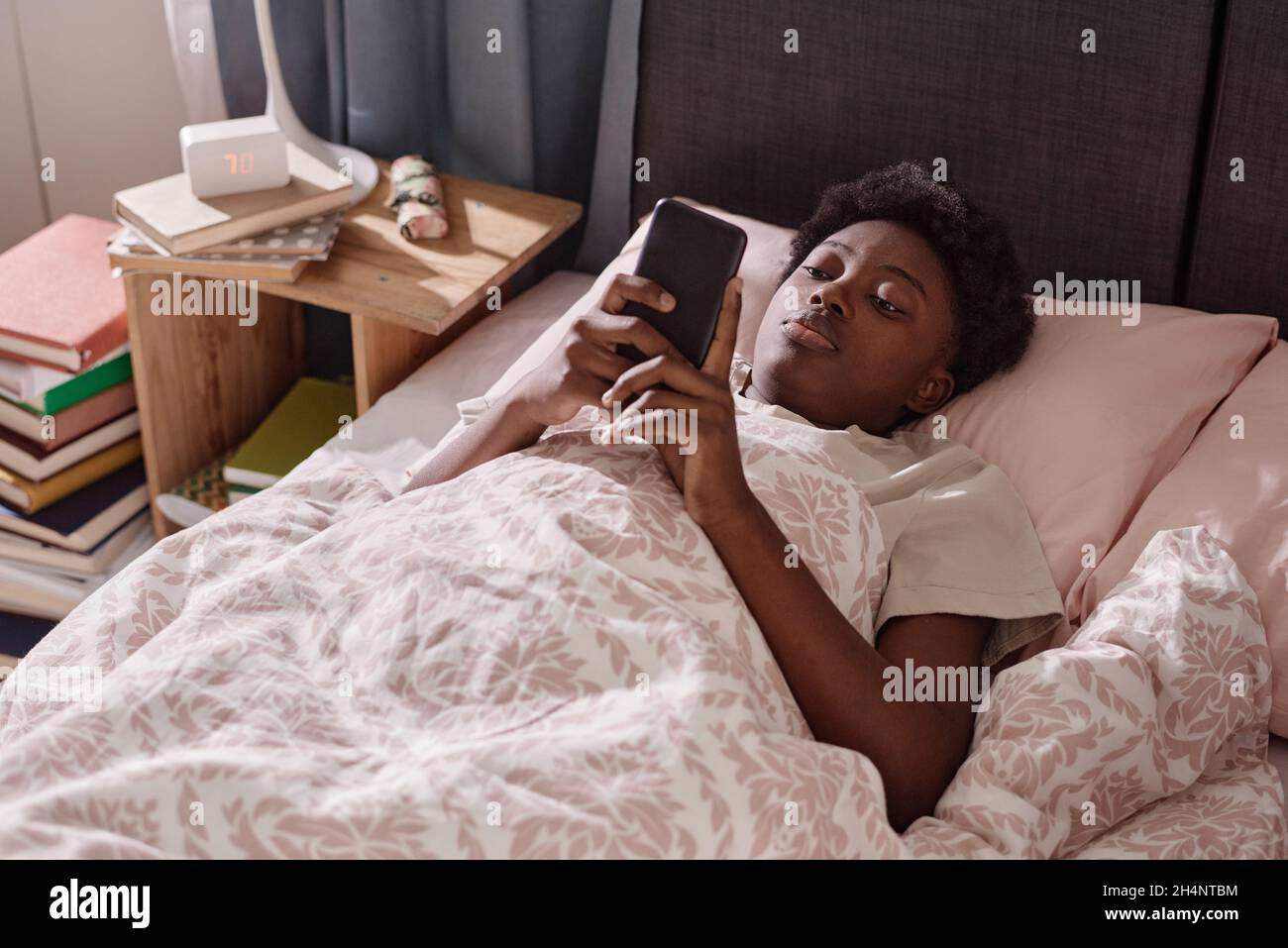 African young woman texting message on her mobile phone while lying on ...