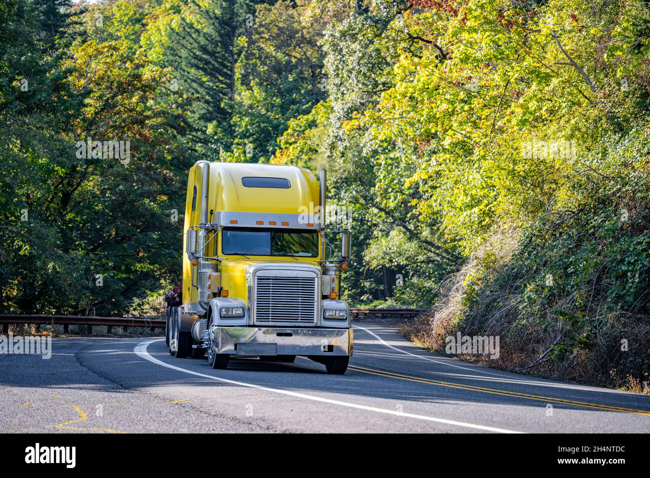 Powerful yellow big rig classic semi truck transporting fixed by slings ...