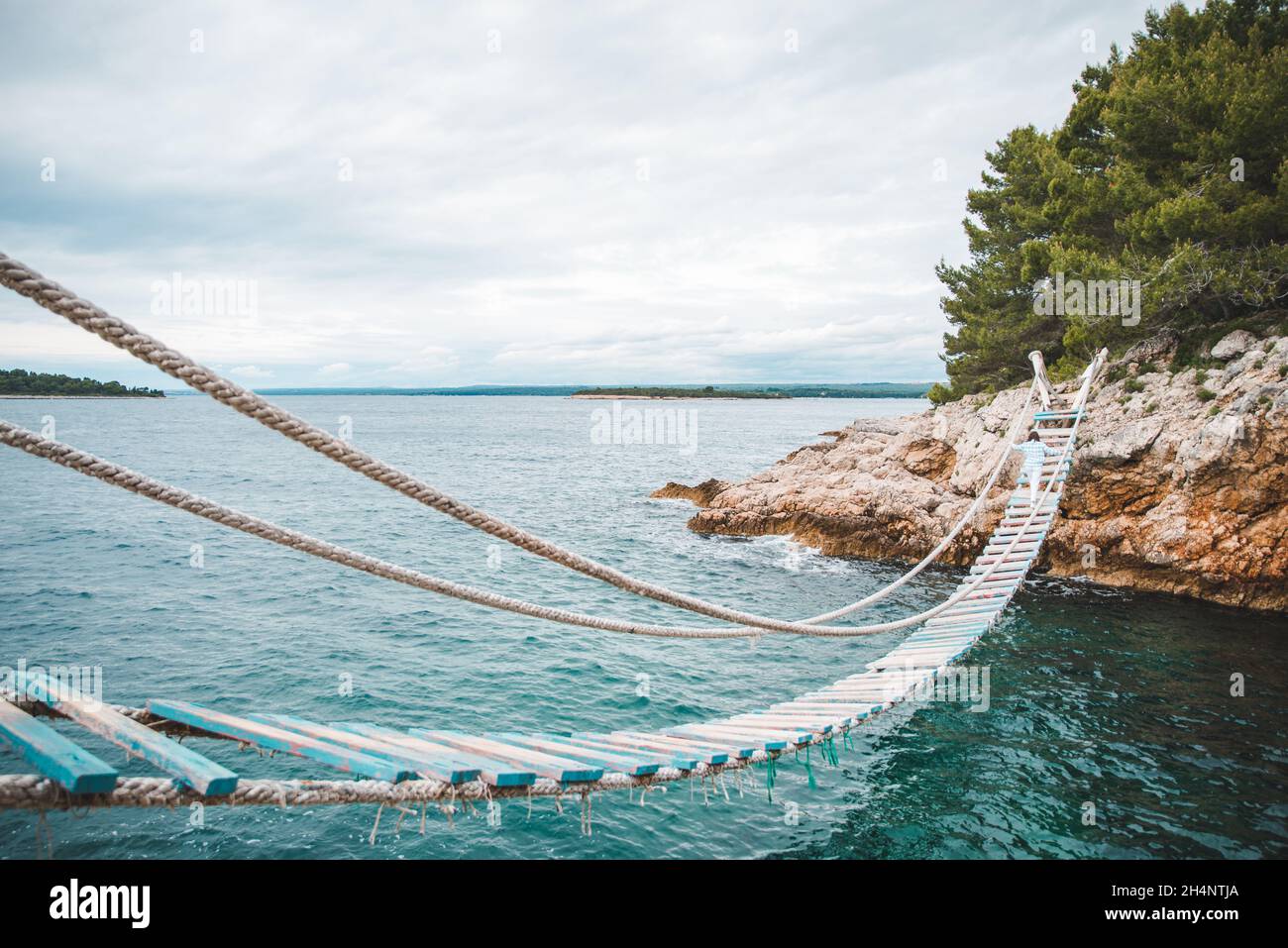 woman crossing suspension bridge sea on background summer time Stock ...